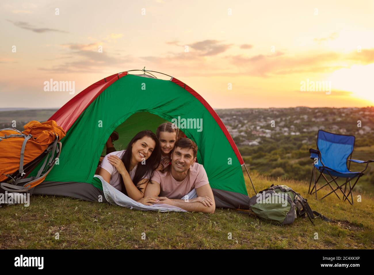 Happy family with child on camping trip relaxing inside tent. Caring ...