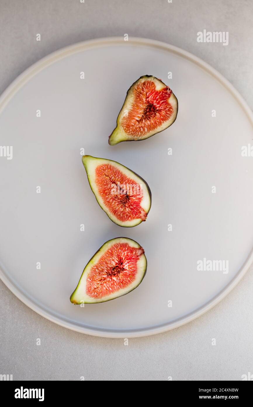 Topview image of figs cut in half in white ceramic plate over gray ...