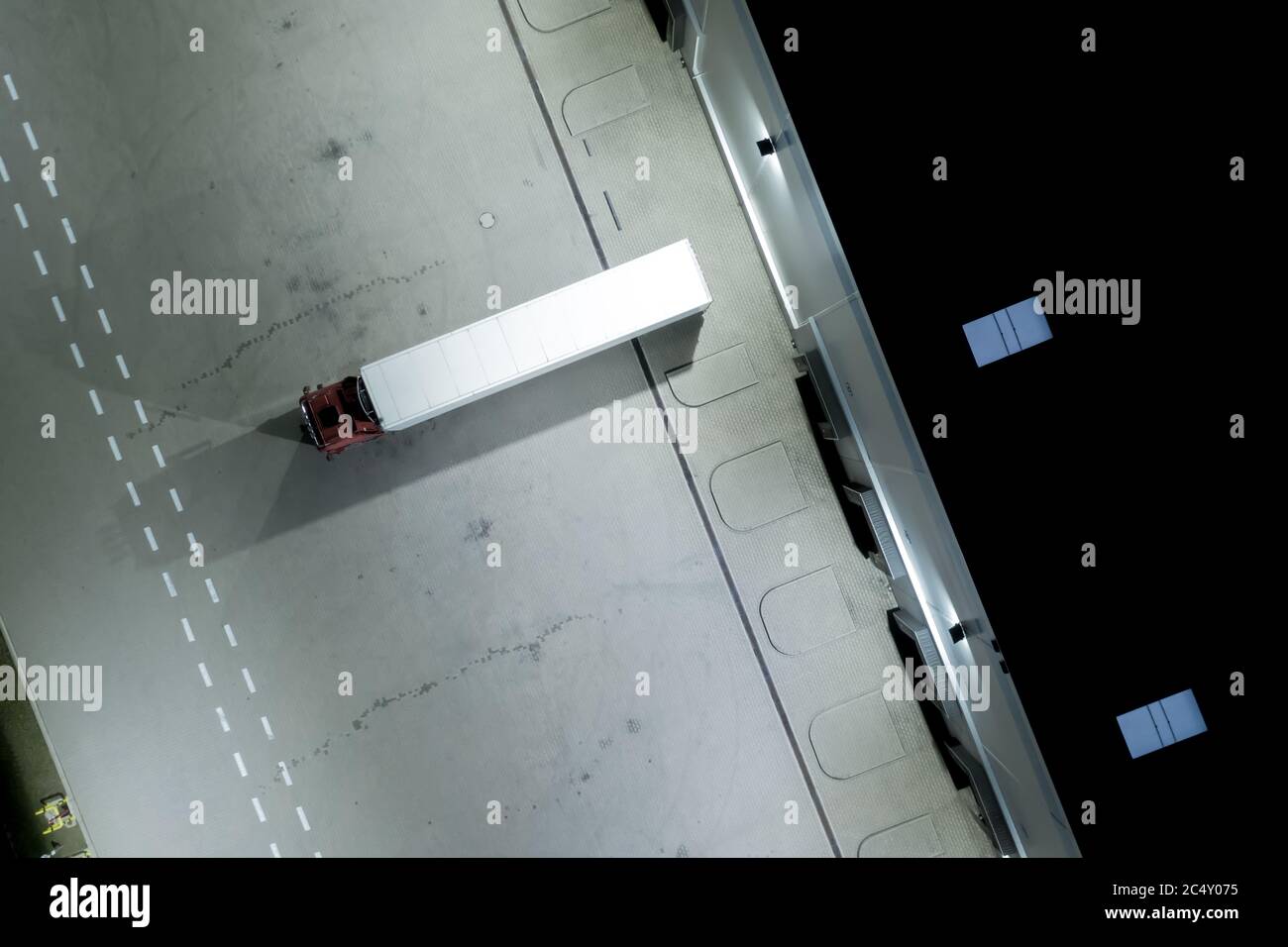 Night Aerial top view of truck and cargo trailer unloading in logostics ...