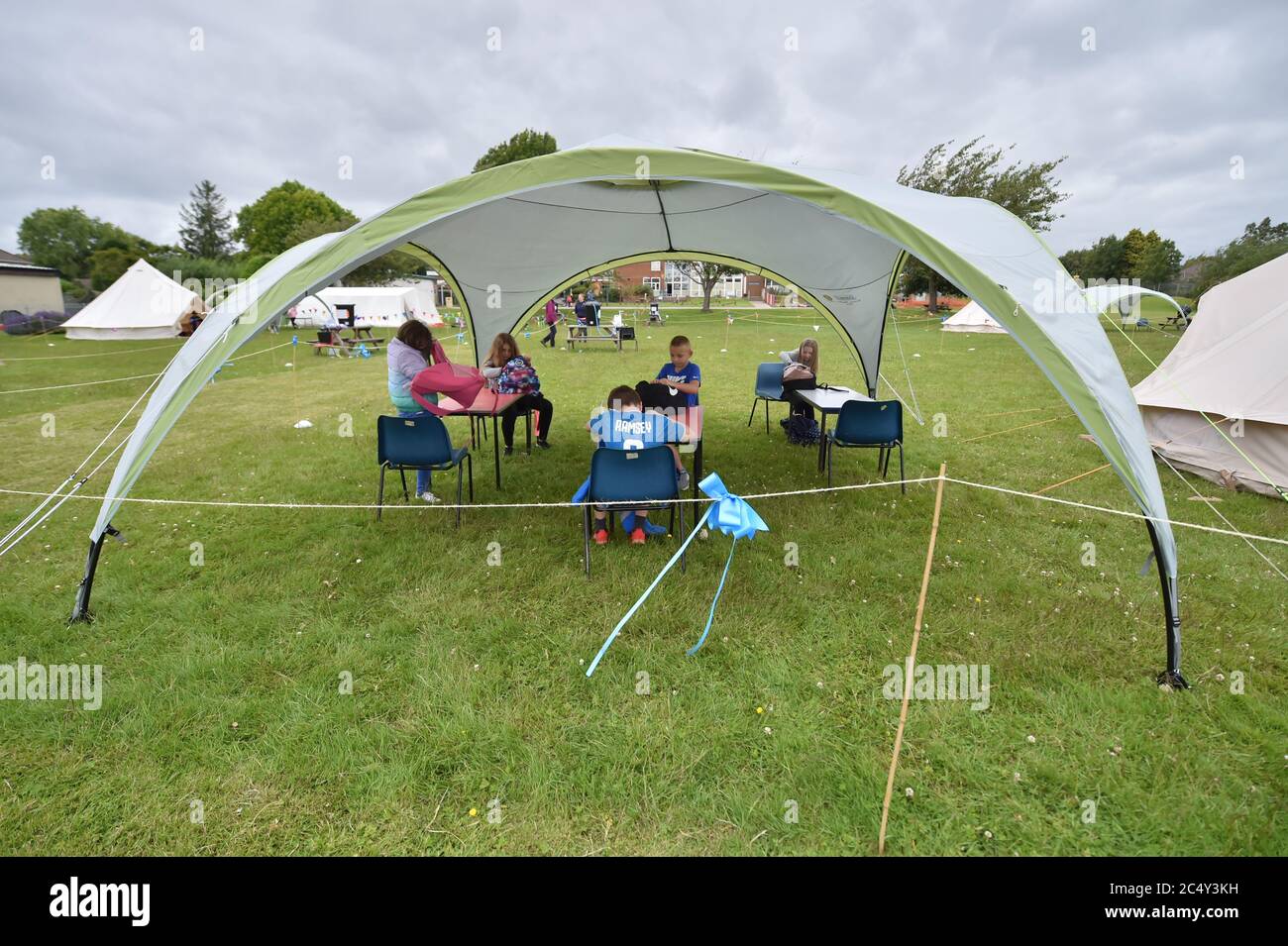Children check their bags in a canopy, which is a makeshift socially ...