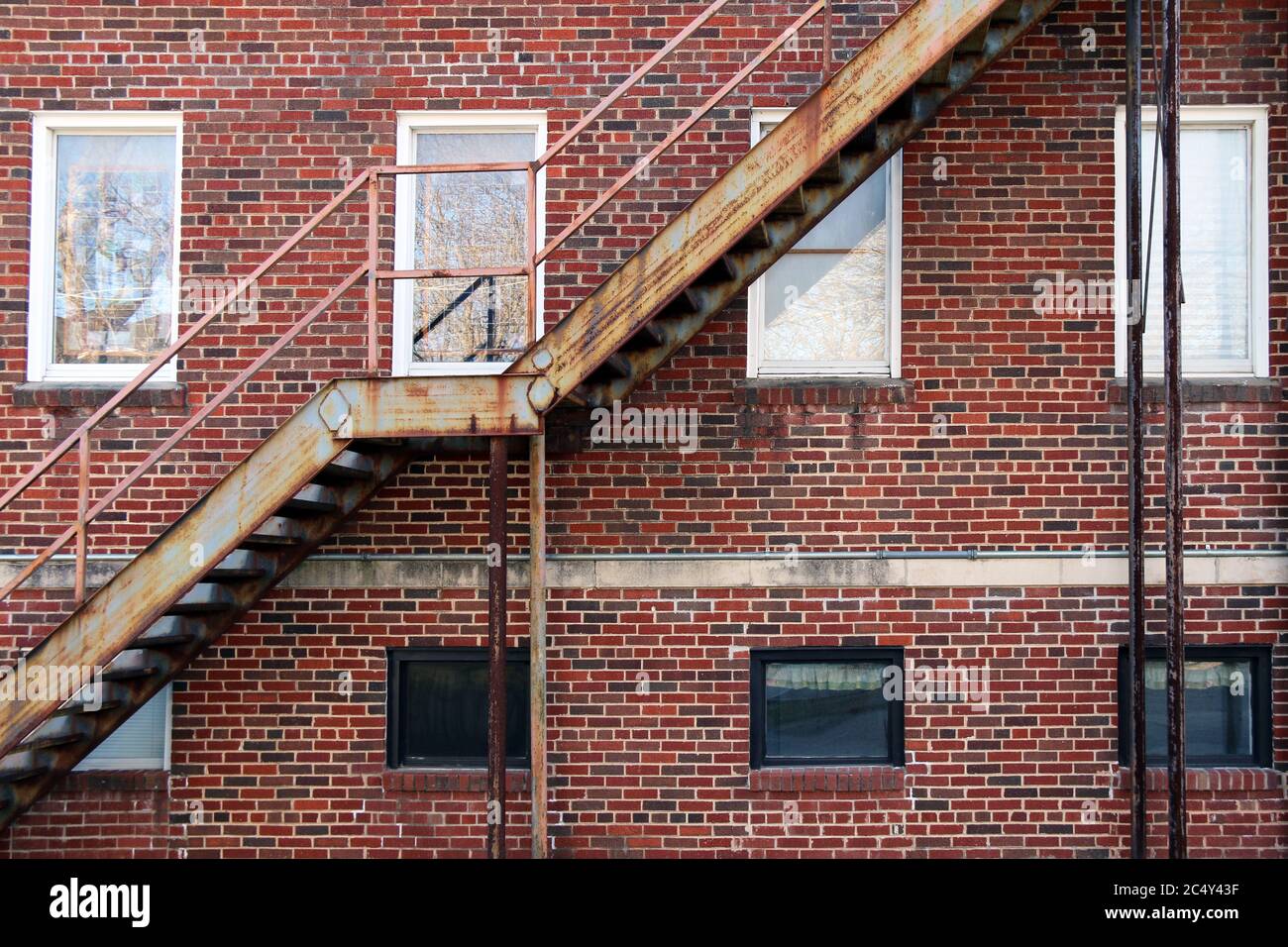set of back alley rusted fire escape stairs in front of white windows ...