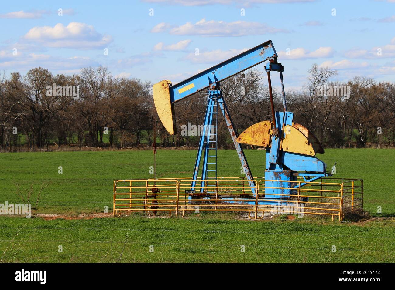 a bright painted old abandoned oil well derrick in a green meadow ...