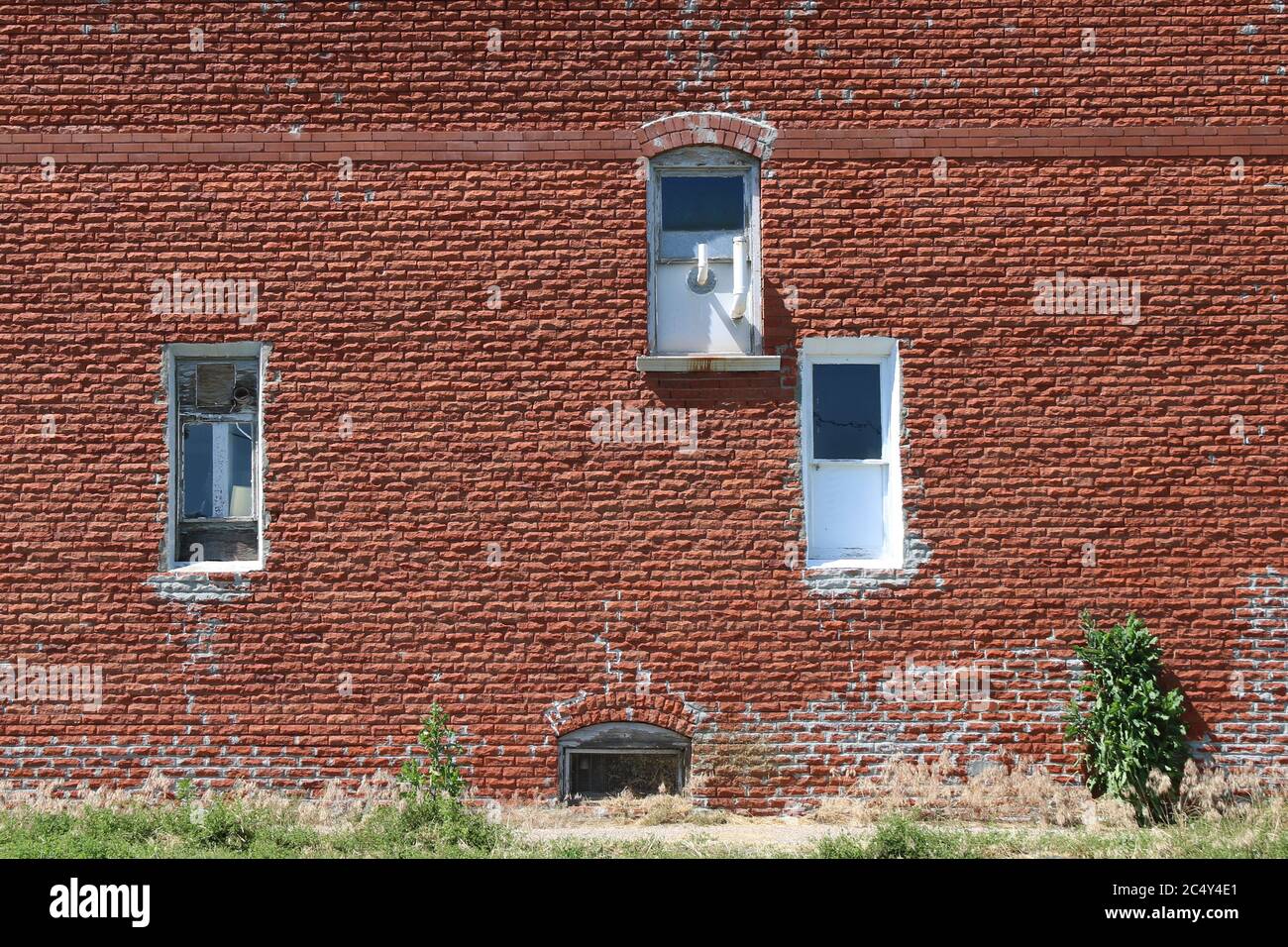 several old white vintage warehouse windows on a red brick building ...