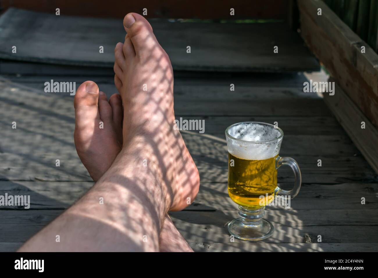 Feet of a resting man with a mug of light beer on a wooden floor Stock ...