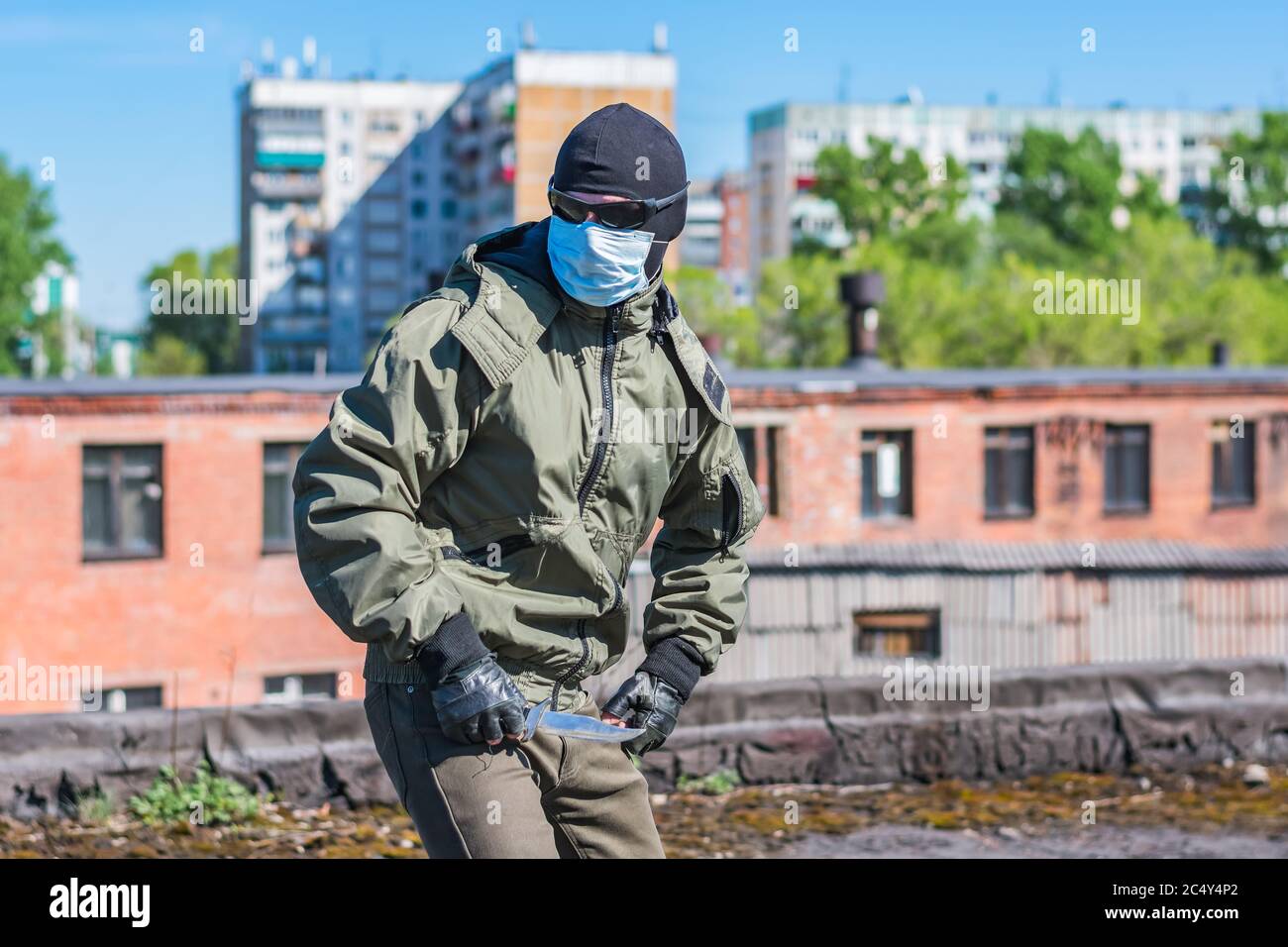 Runaway armed criminal in balaclava and medical mask Stock Photo - Alamy