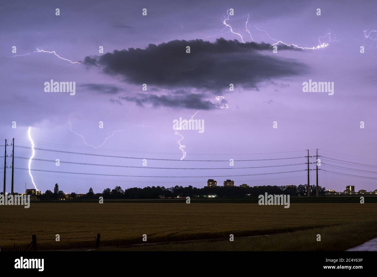 Lightning bolts strike down near power lines during a stormy night ...