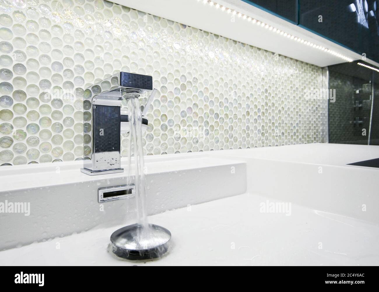 modern designer tap with running water and mosaic wall Stock Photo - Alamy