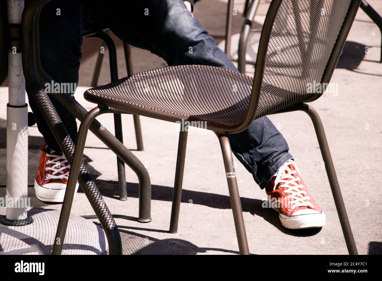 An effortlessly sitting human beside a chair casting shadow upon legs ...