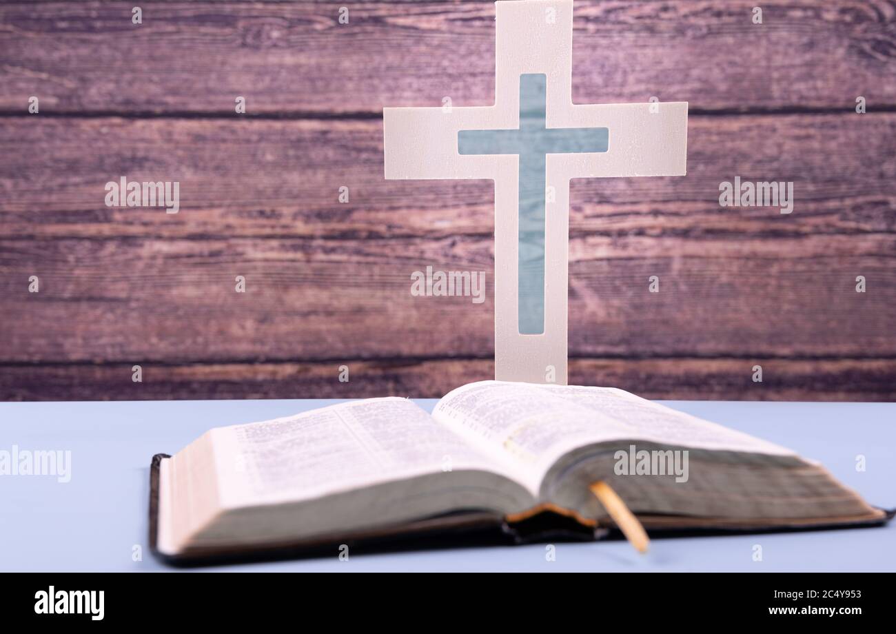Open Bible and wooden cross on a blue table. Copy space. Church concept ...
