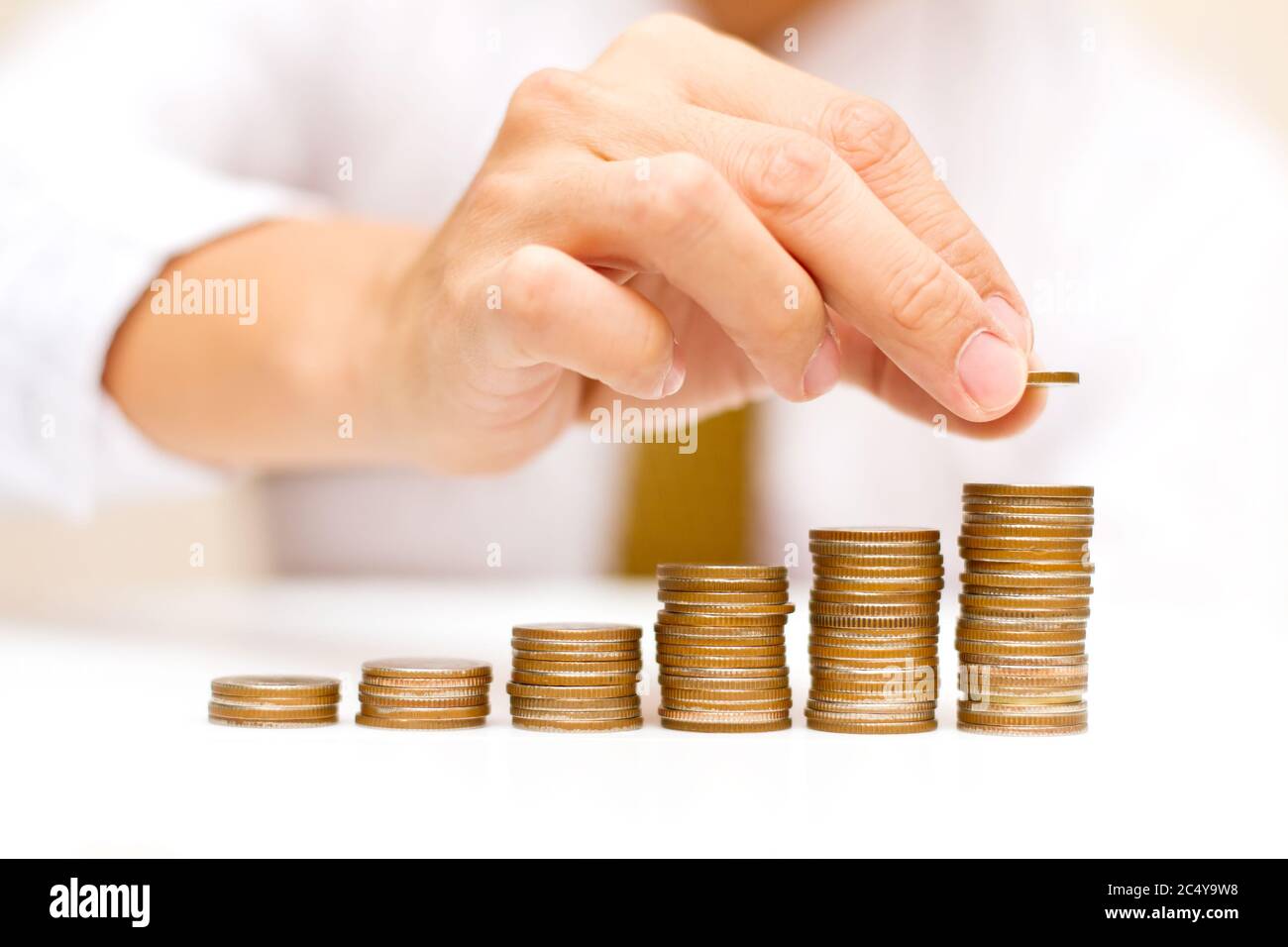 a man stacking coins forming a graph Stock Photo - Alamy