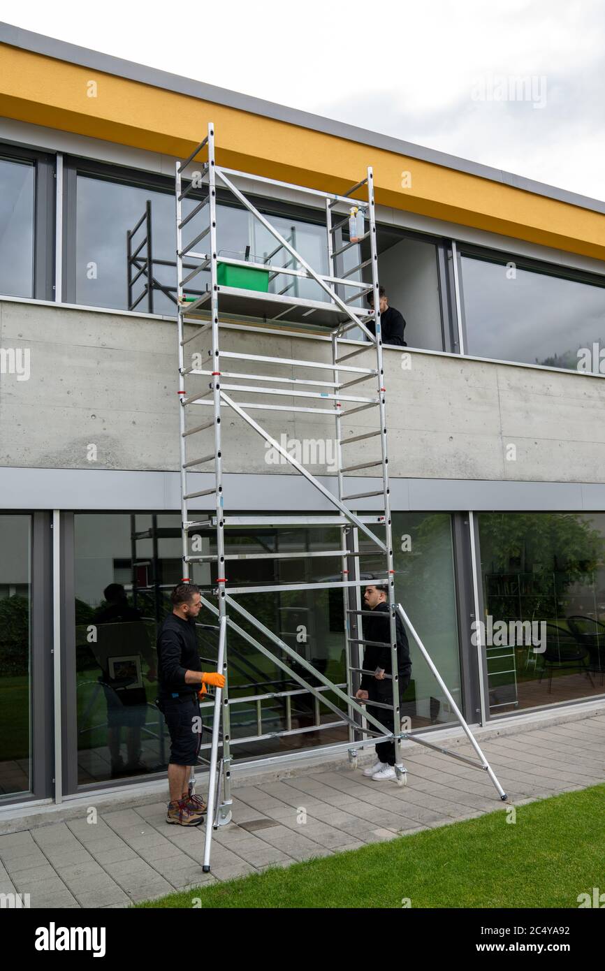 Two professional window washers move a portable scaffolding along a ...