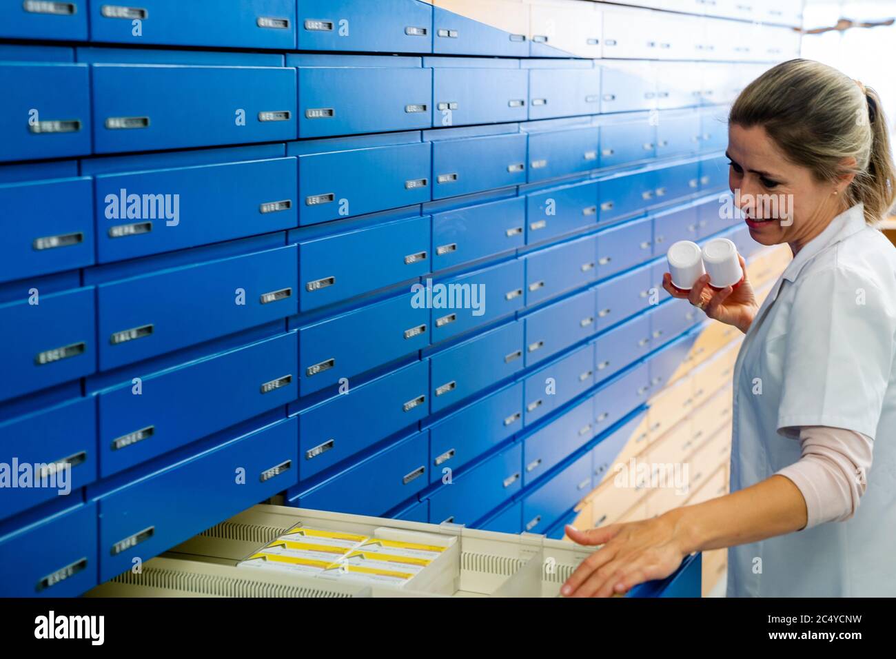 A blonde pharmacist checking a medical product and precription in one ...