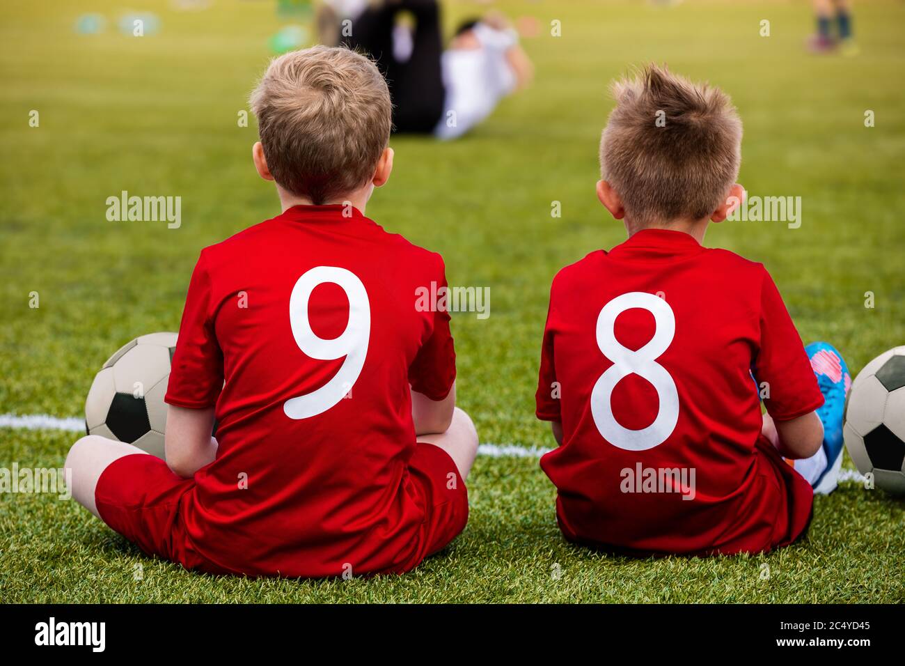 Two children in red football uniforms. Kids playing sports on the grass ...
