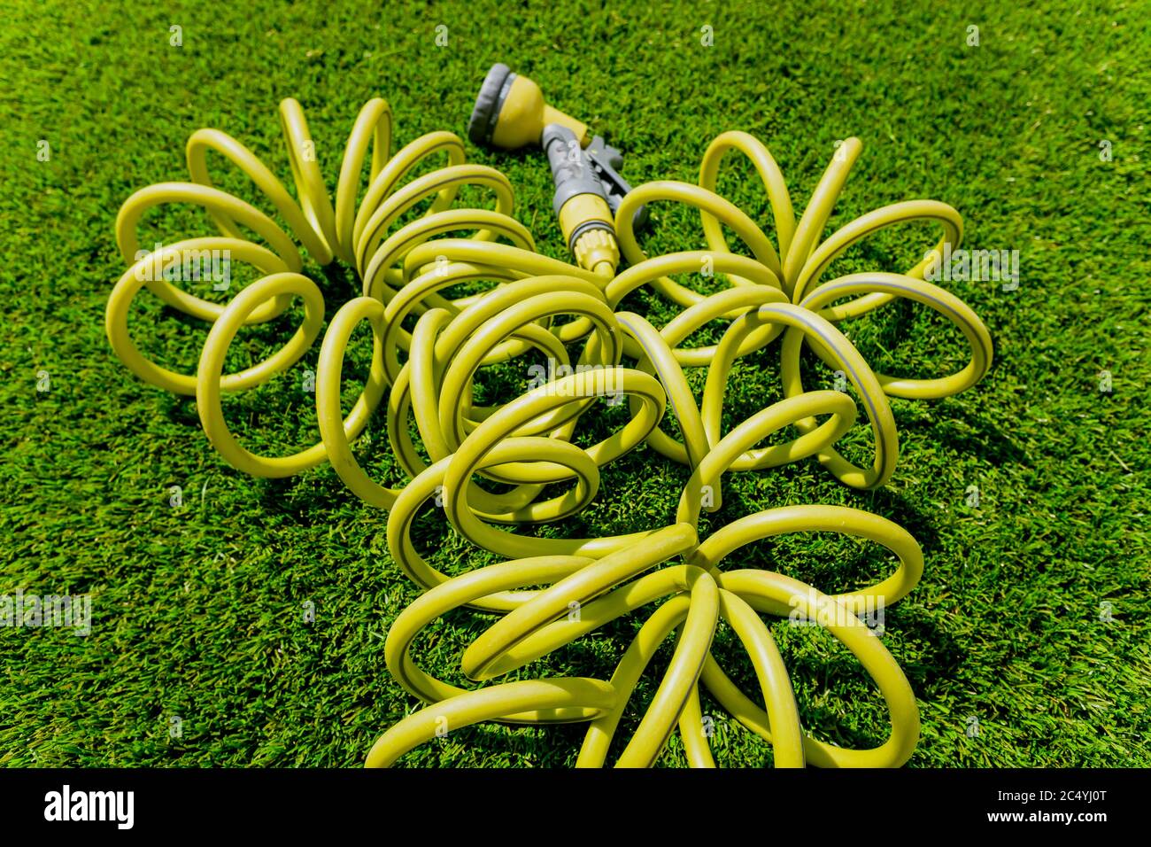 Coiled hose for watering the lawn of a garden Stock Photo - Alamy