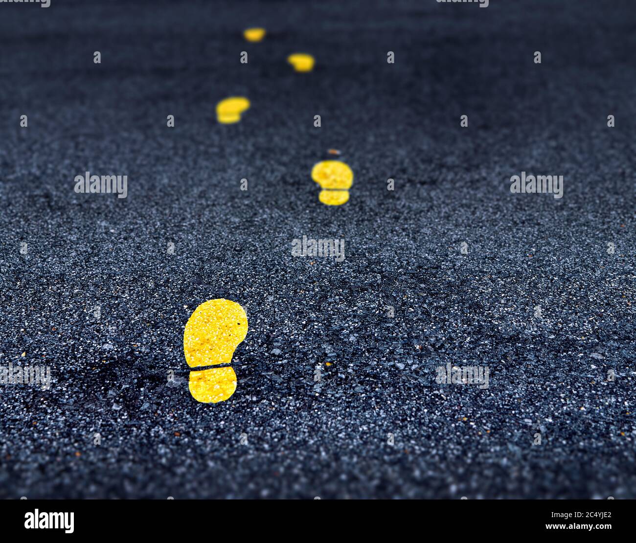 Yellow footprint signs on an asphalt road. Painted footprints show the ...