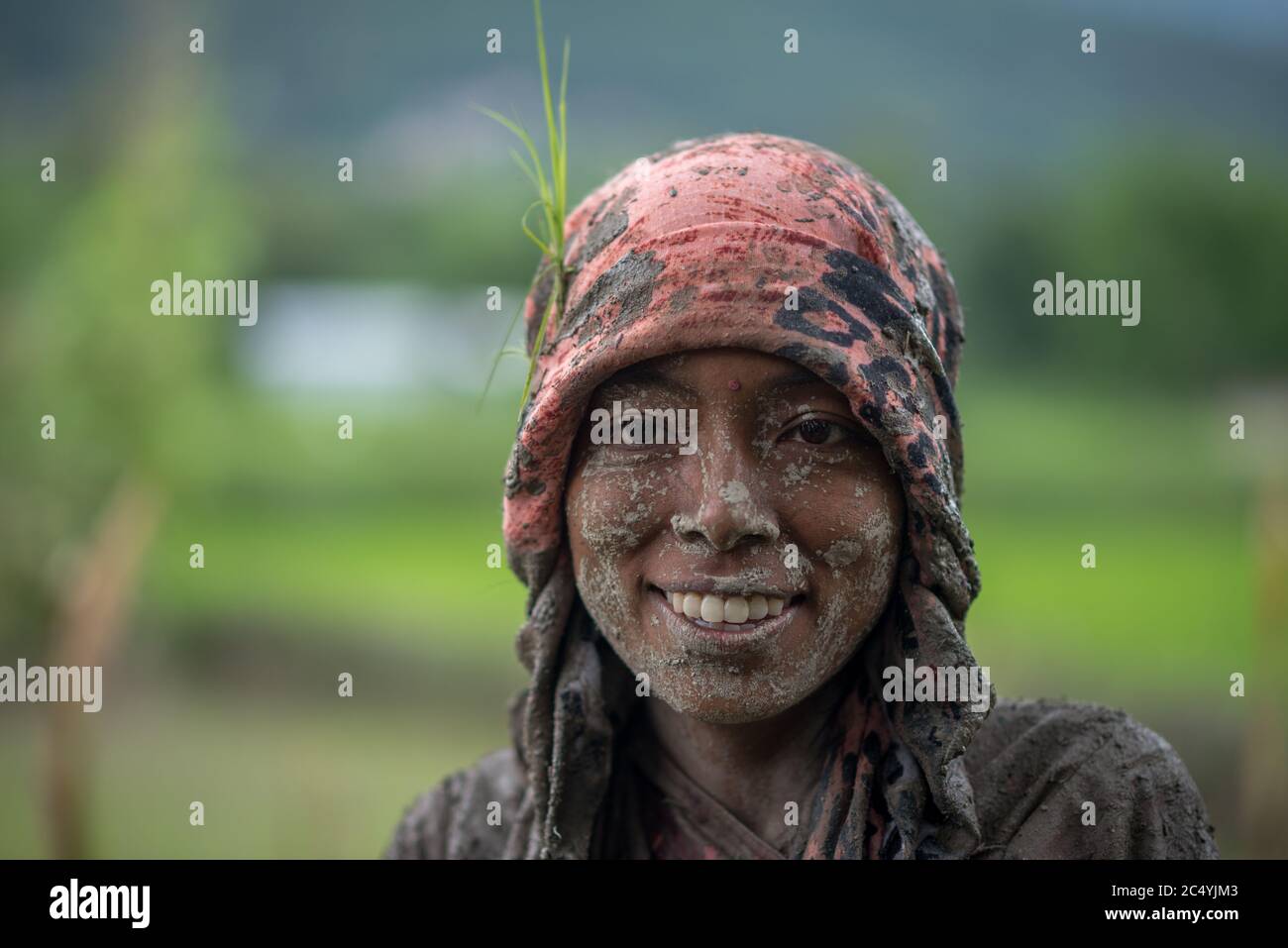 A woman covered in mud smiles in a rice paddy field during the National ...