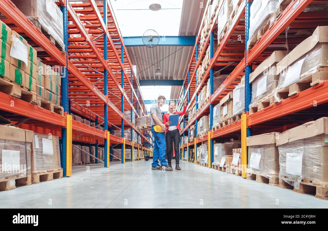 Worker team standing between high racks in logistics warehouse Stock ...