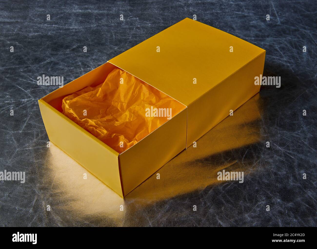 View of an open yellow gift box with packaging paper inside on a silver ...