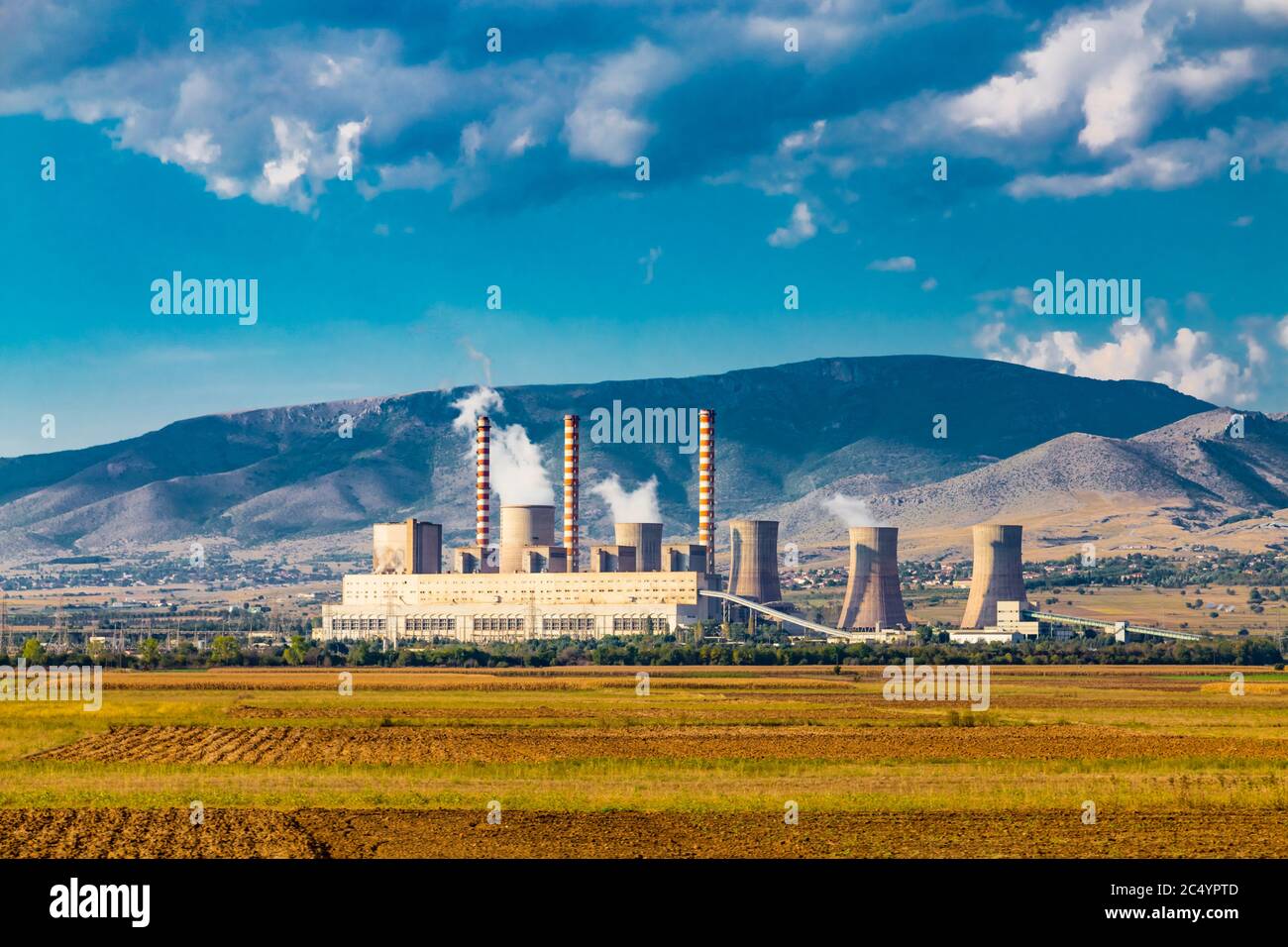 Steaming coal power plant over yellow agriculture field on the ...