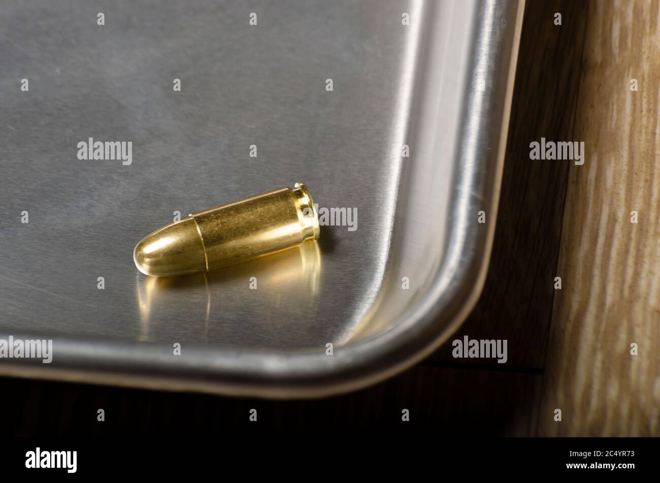 a single full metal jacketed cartridge sits in the corner of a silver ...