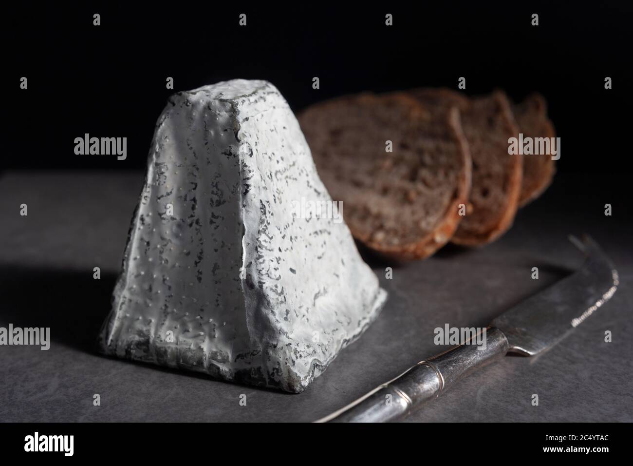 An ash covered goat cheese pyramid with sourdough bread slices Stock ...