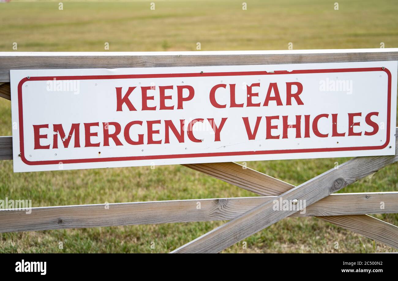 Red and white sign on a wooden gate 'Keep clear Emergency Vehicles ...