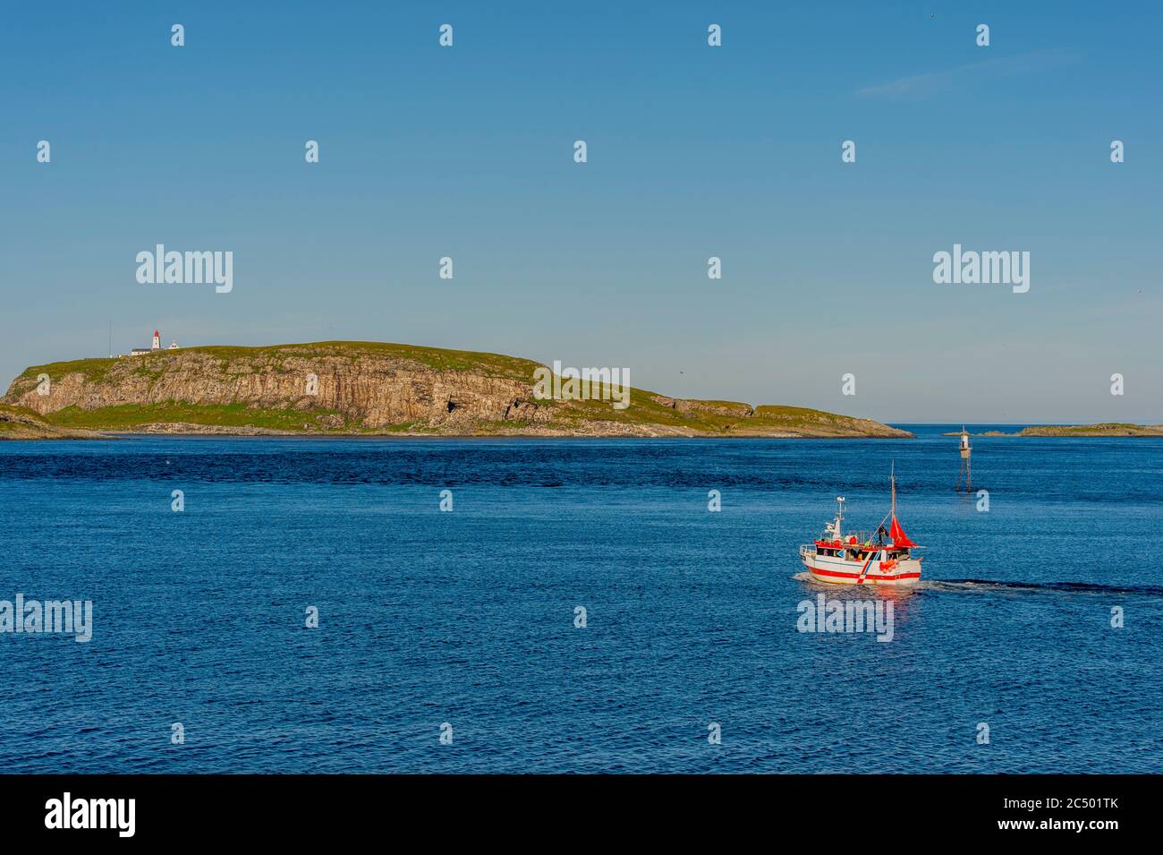 Fishing boat with lighthouse on an island in background at Vardo, a ...