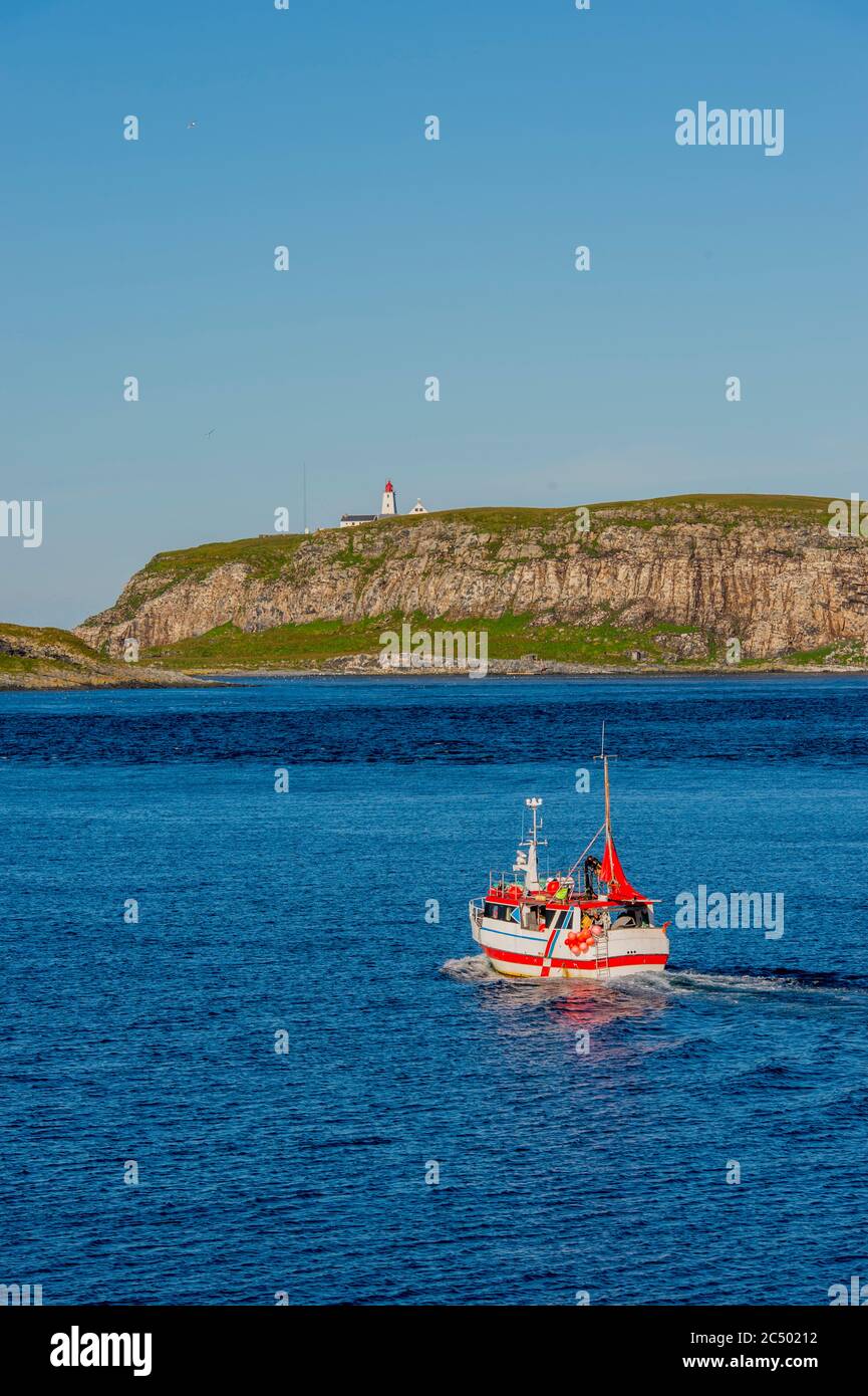 Fishing boat with lighthouse on an island in background at Vardo, a ...
