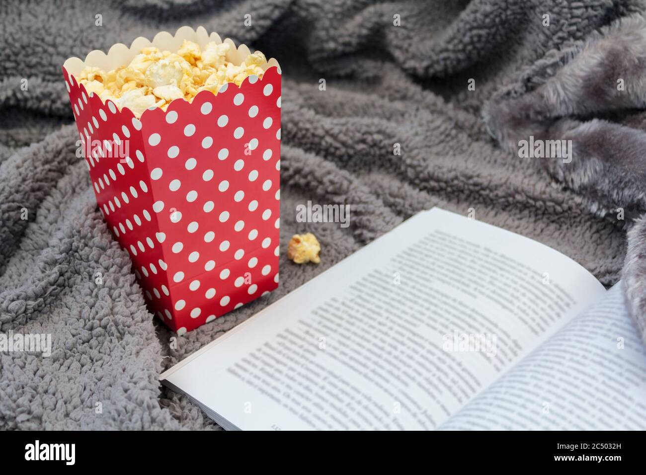 Popcorn box and open book on warm blanket Stock Photo - Alamy