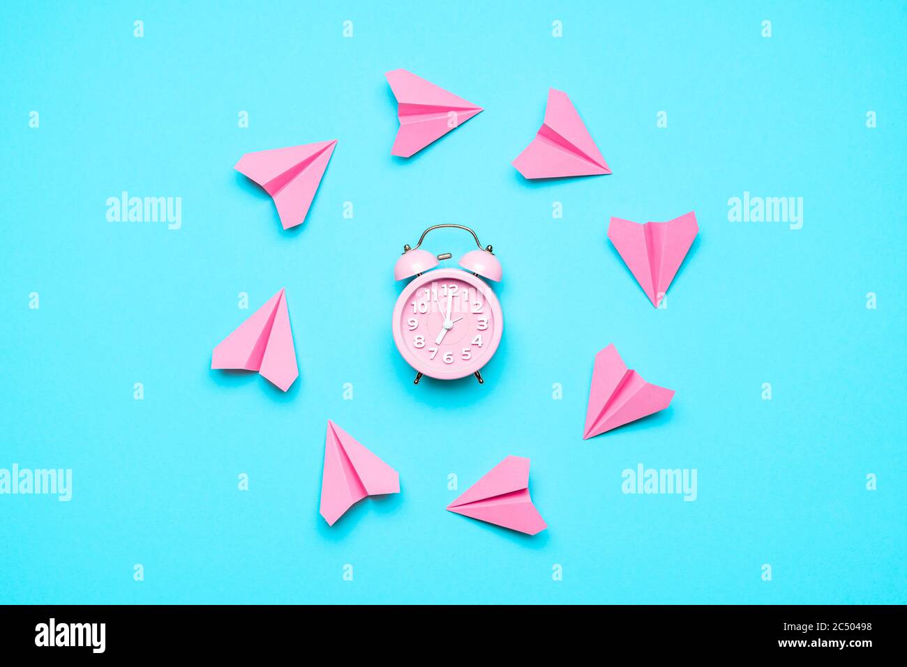 Time flying concept with pink paper airplanes and alarm clock on a blue ...