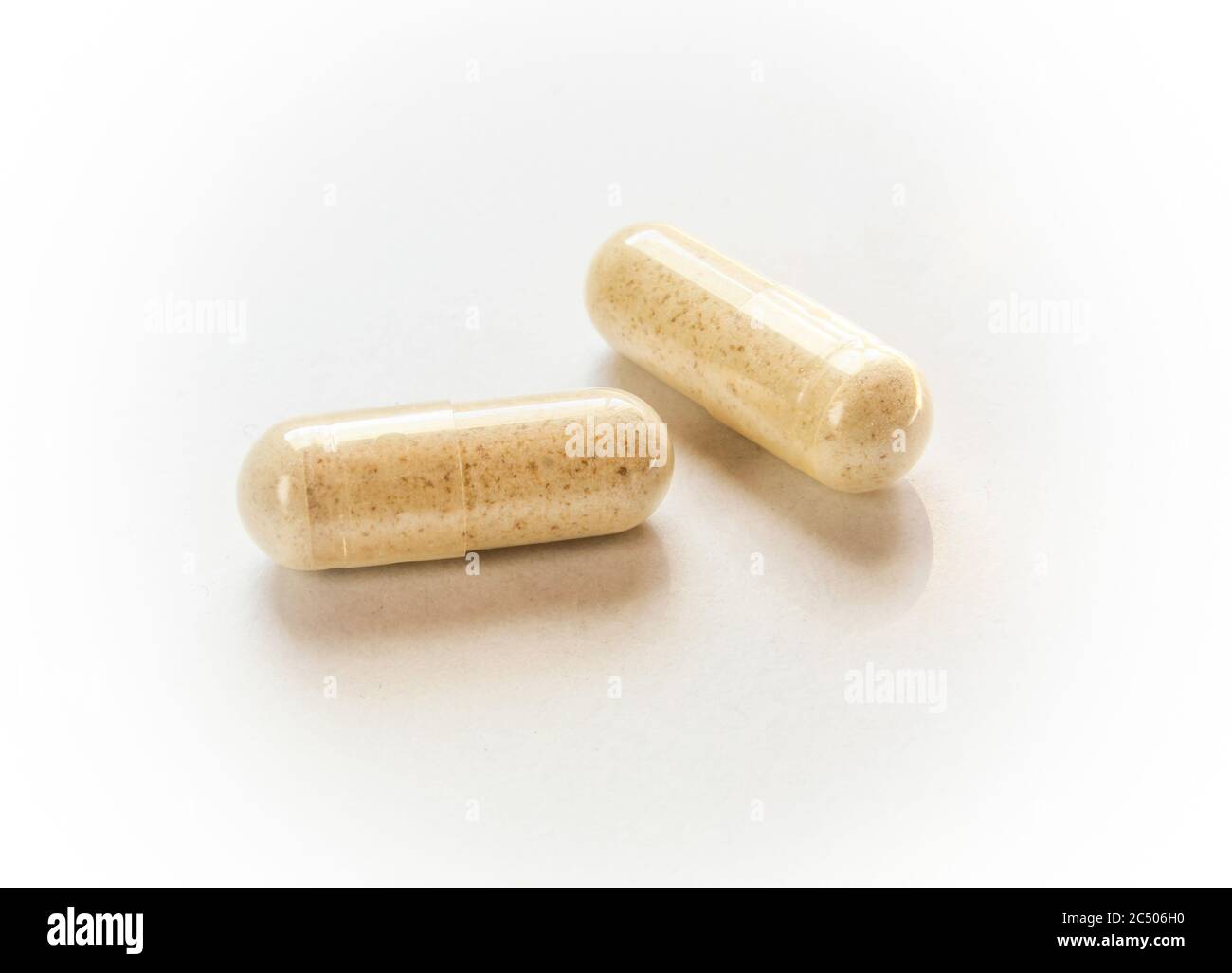 Two transparent capsules filled with brown powder on white Stock Photo ...