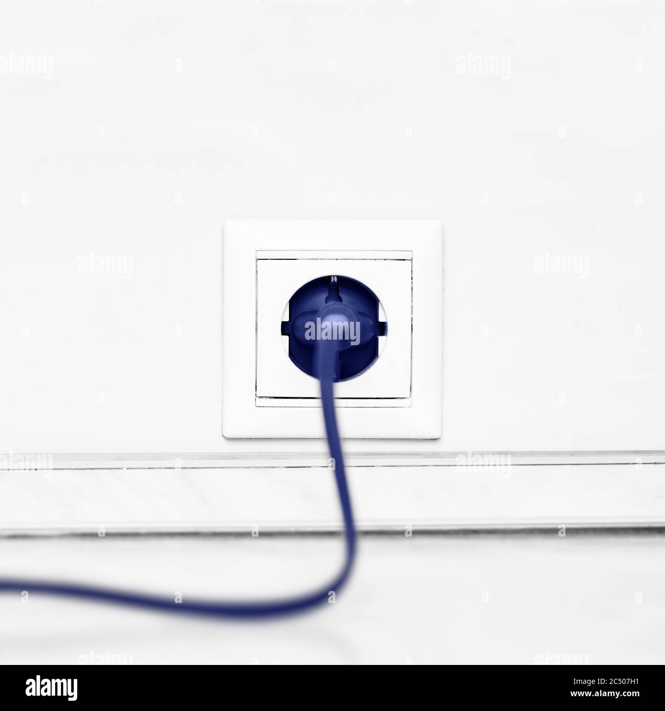 Electric white socket and one plugged in power cord on white wall ...
