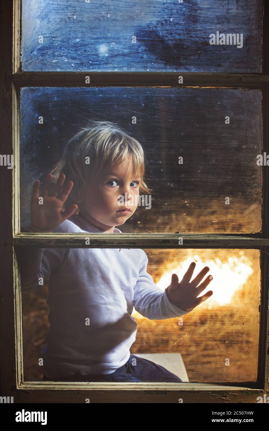 Blond child behind the window, looking outside at the moon Stock Photo ...