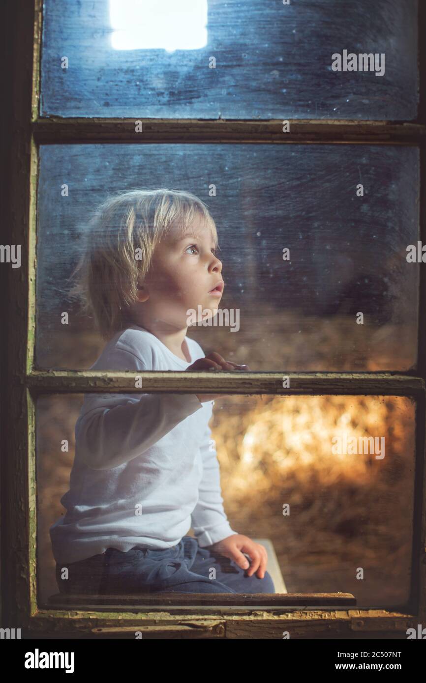 Blond child behind the window, looking outside at the moon Stock Photo ...