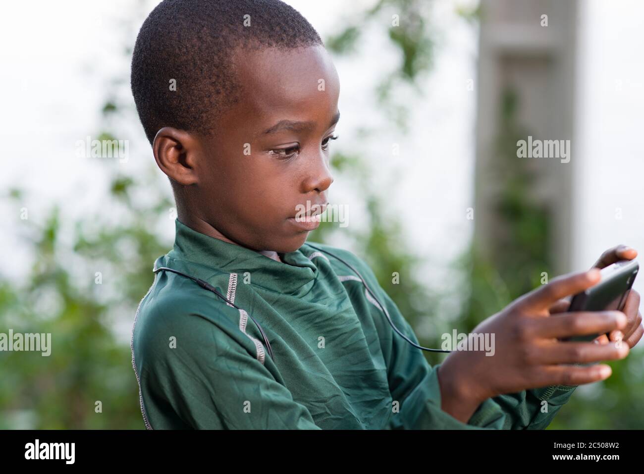 Young boy child with mobile phone outdoors. Child looking at the screen ...