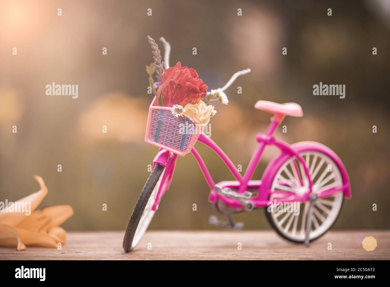 Pink vintage bicycle with basket and flowers leaning against wooden ...