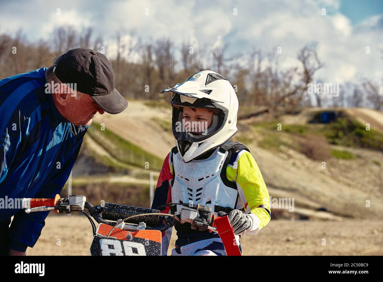 kids riding at motobike, junior competition on motorcycle. Coach gives ...