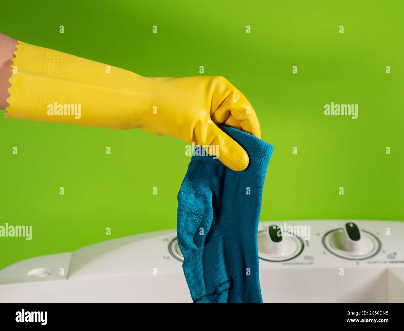 gloved hands washing a blue sock and green background Stock Photo - Alamy