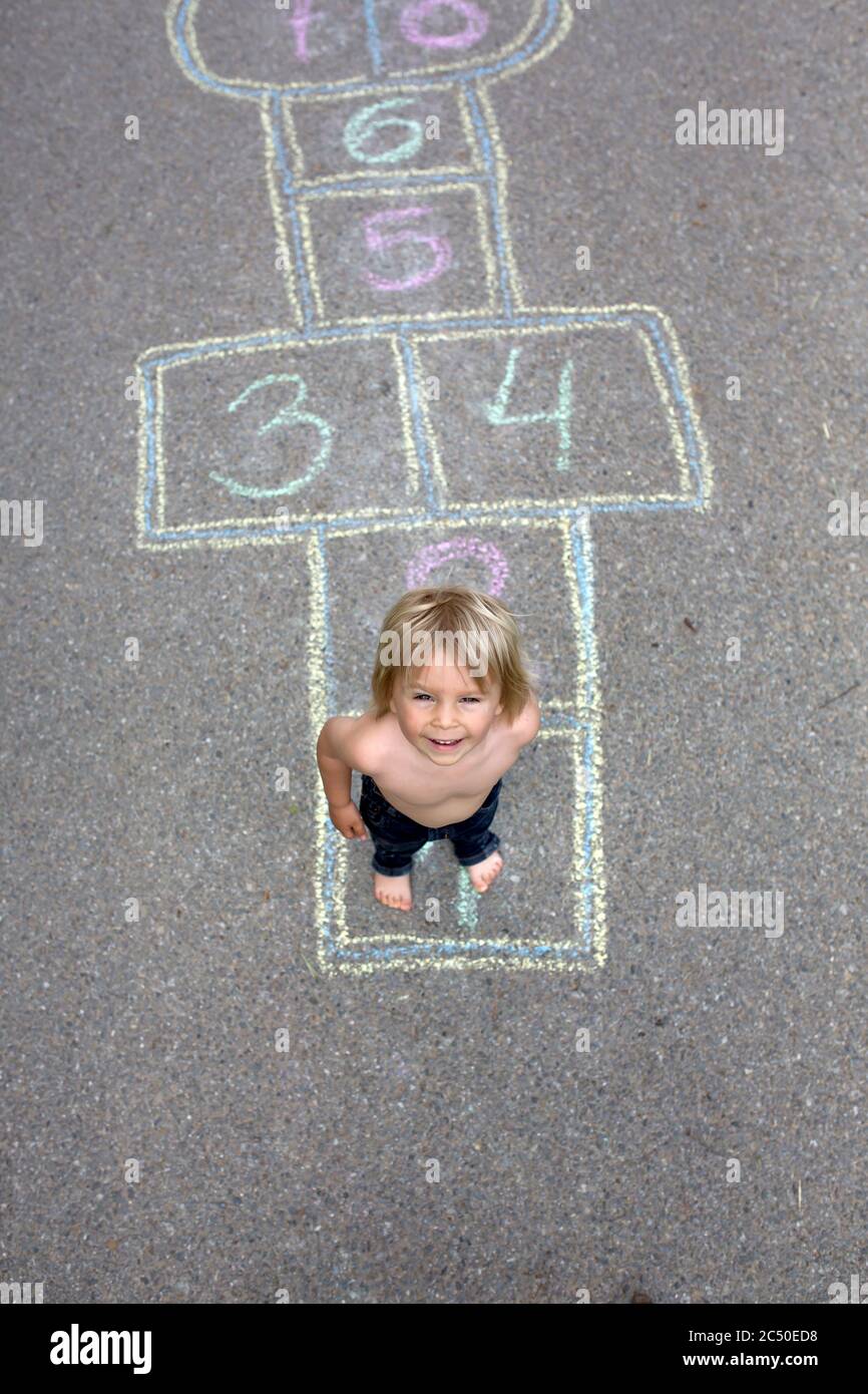 Child, blond boy, playing hopscotch on the street, summertime Stock ...