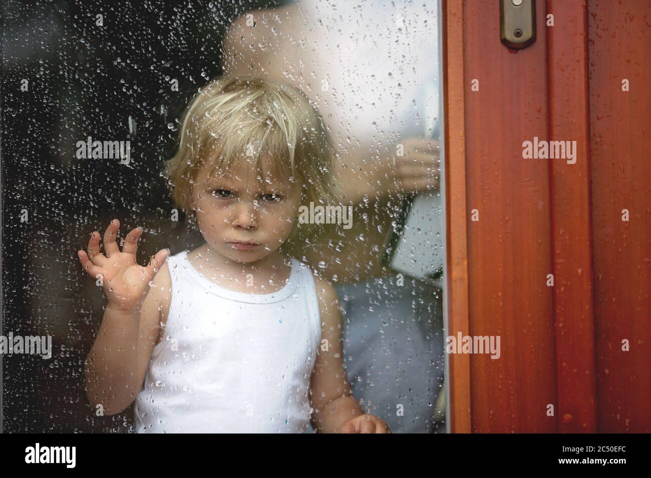 Sad child behind the window on a rainy day Stock Photo - Alamy