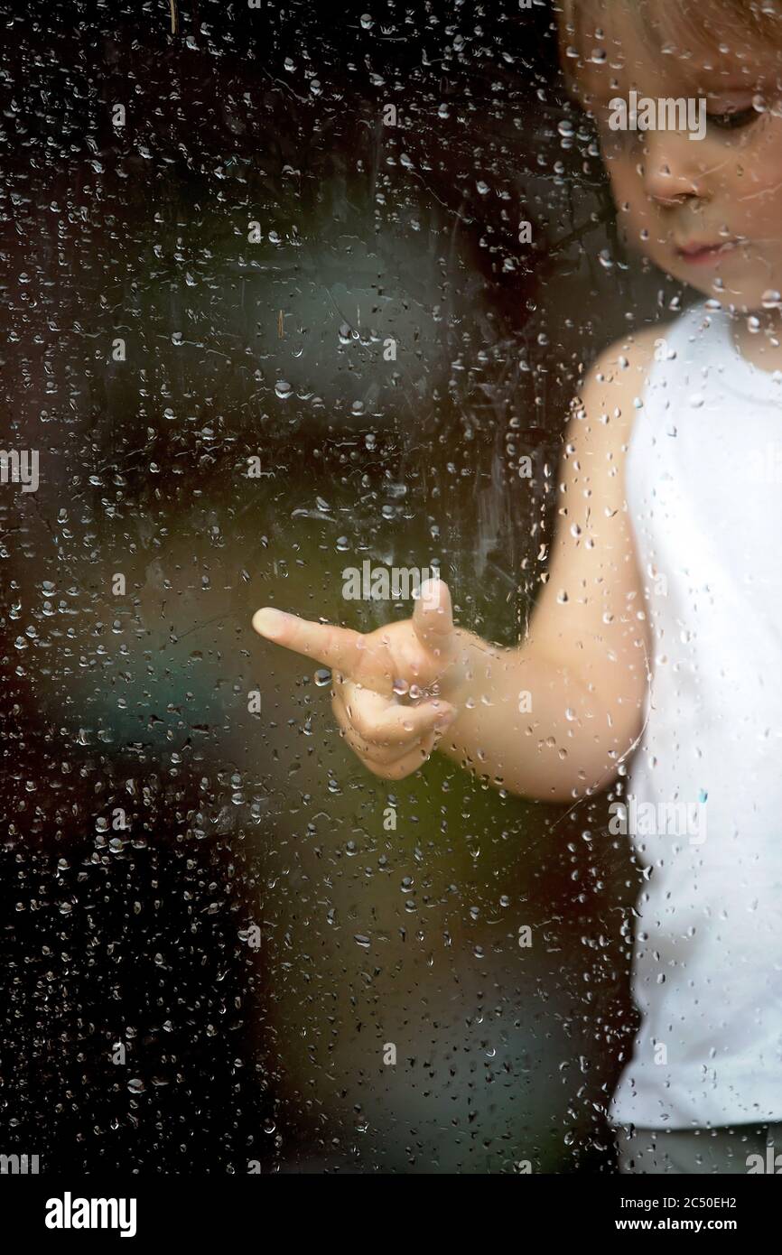 Sad child behind the window on a rainy day Stock Photo - Alamy