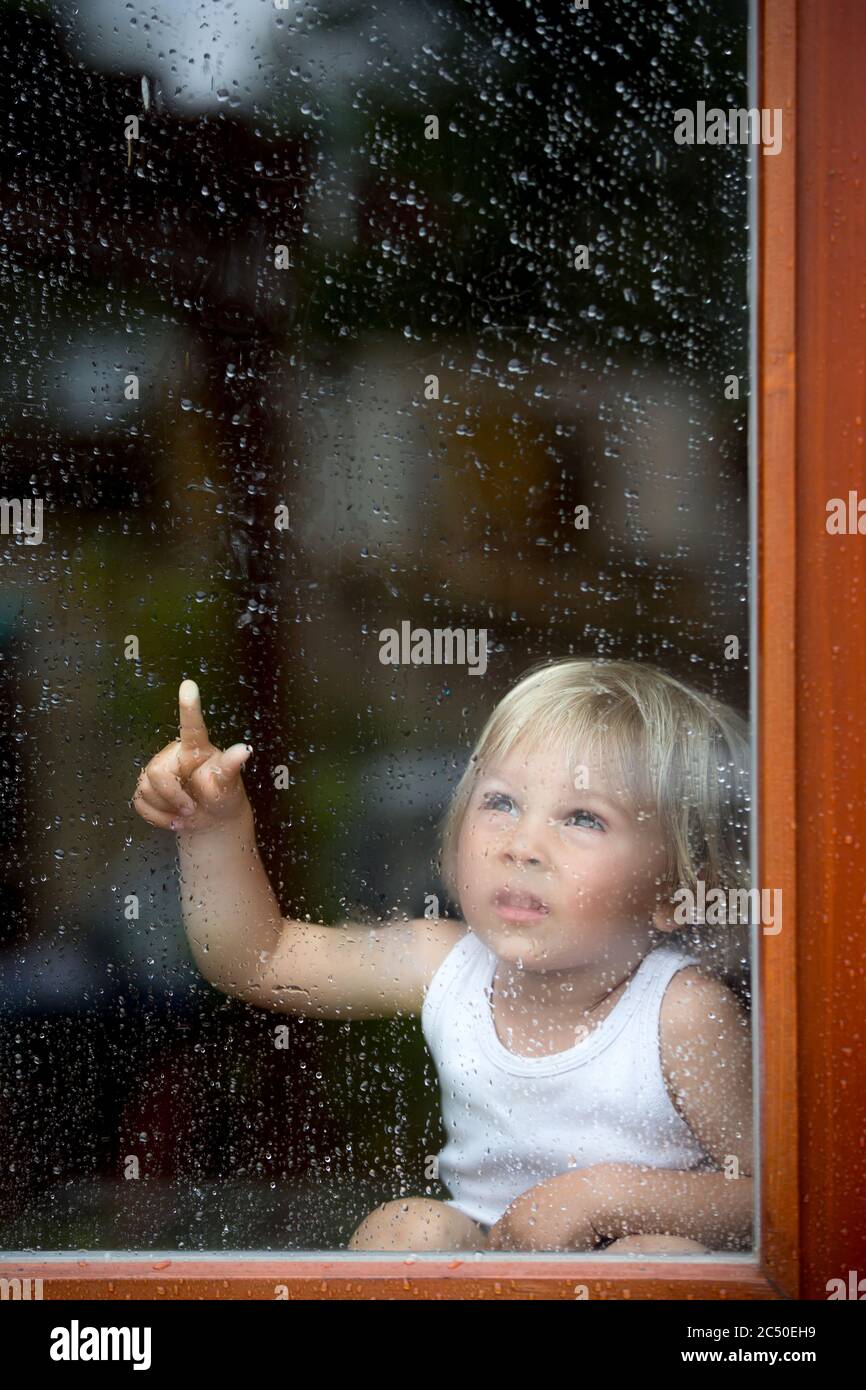 Sad child behind the window on a rainy day Stock Photo - Alamy