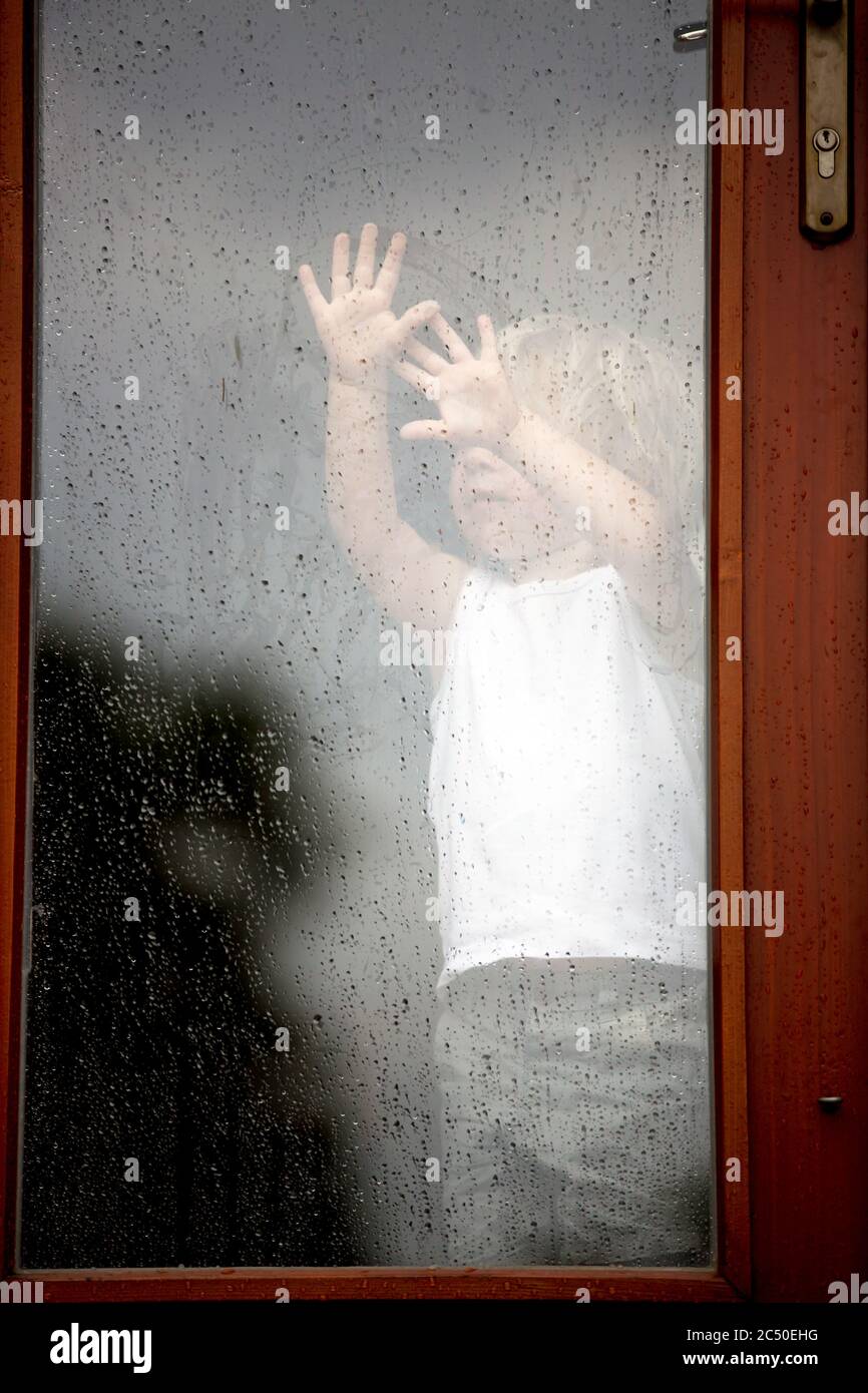 Sad child behind the window on a rainy day Stock Photo - Alamy