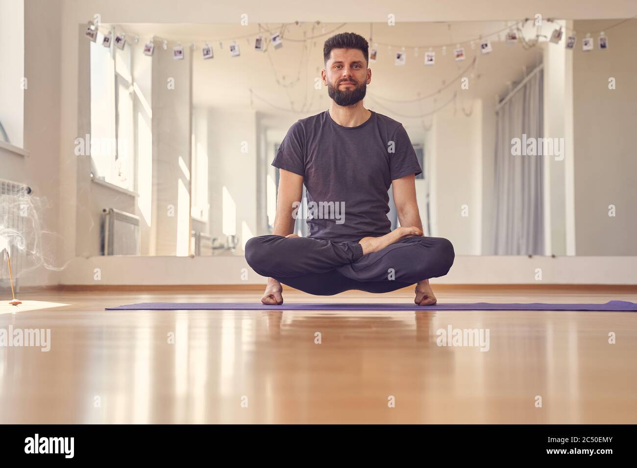 Bearded young man doing lifted lotus or scale pose Stock Photo - Alamy