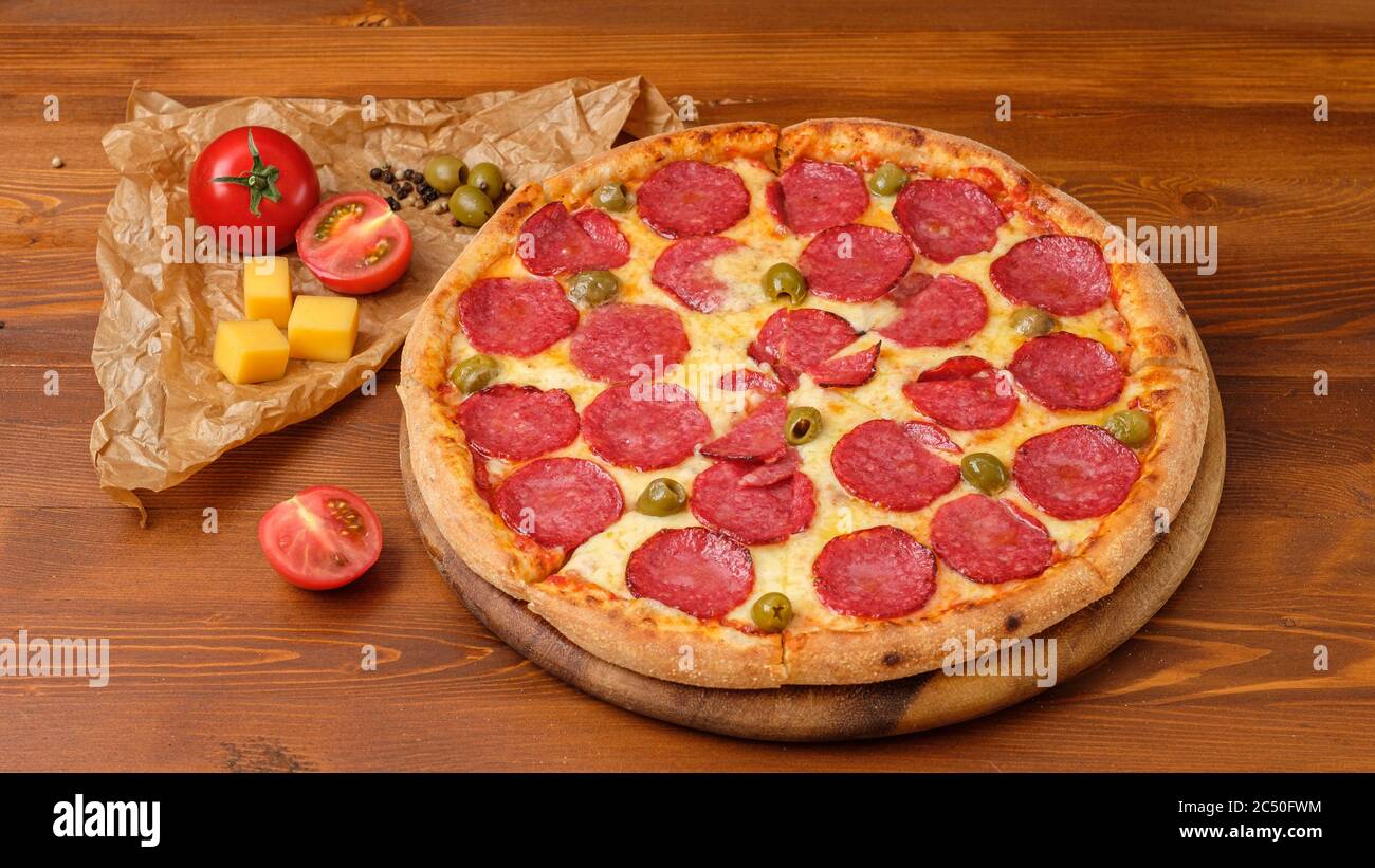 Tasty pizza pepperoni with ingridients on kraft paper lying on wooden ...