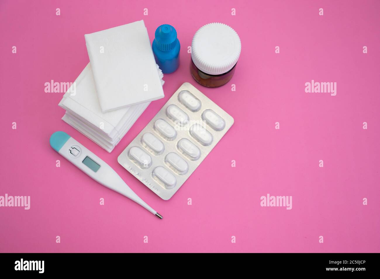 Tissues, nose drops, thermometer, pills and blister on pink background ...