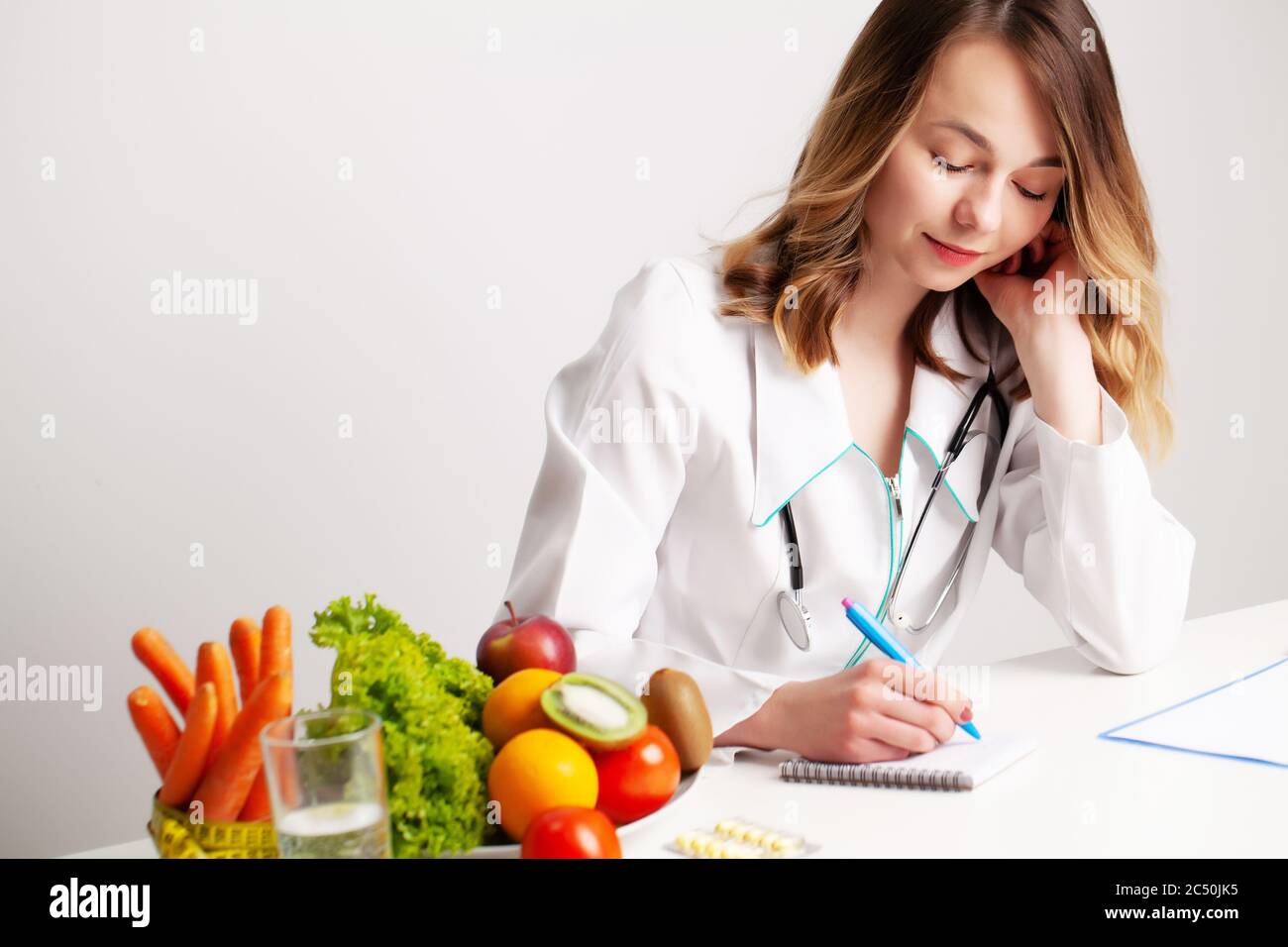 Beautiful young female nutritionist with fresh vegetables and fruits ...