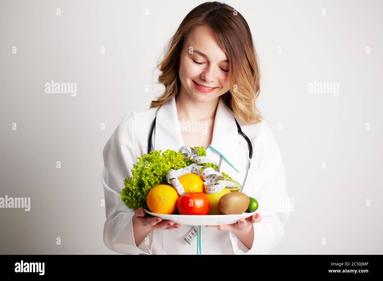 Beautiful young female nutritionist with fresh vegetables and fruits ...