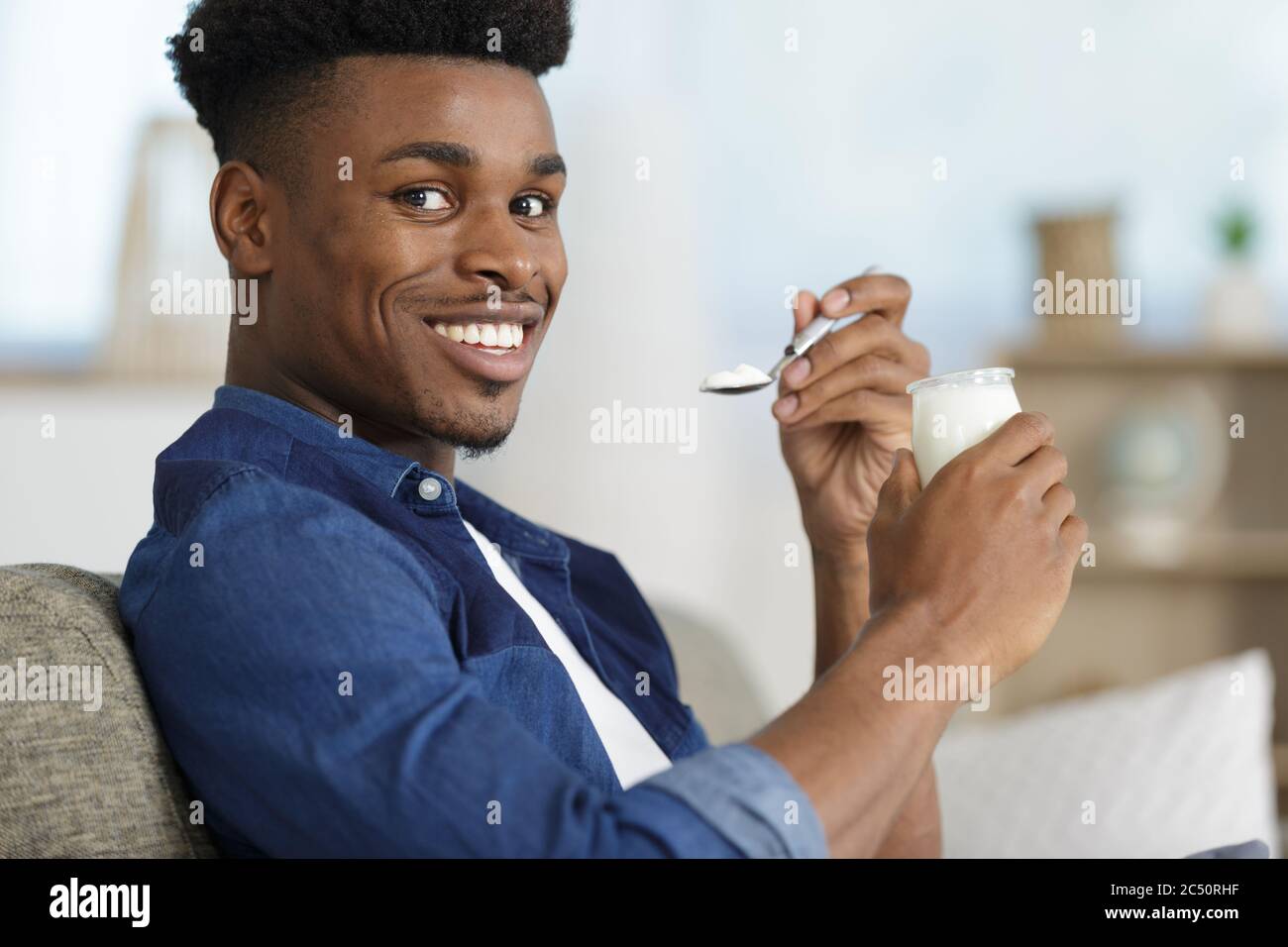 young smiling man eating yogurt Stock Photo - Alamy