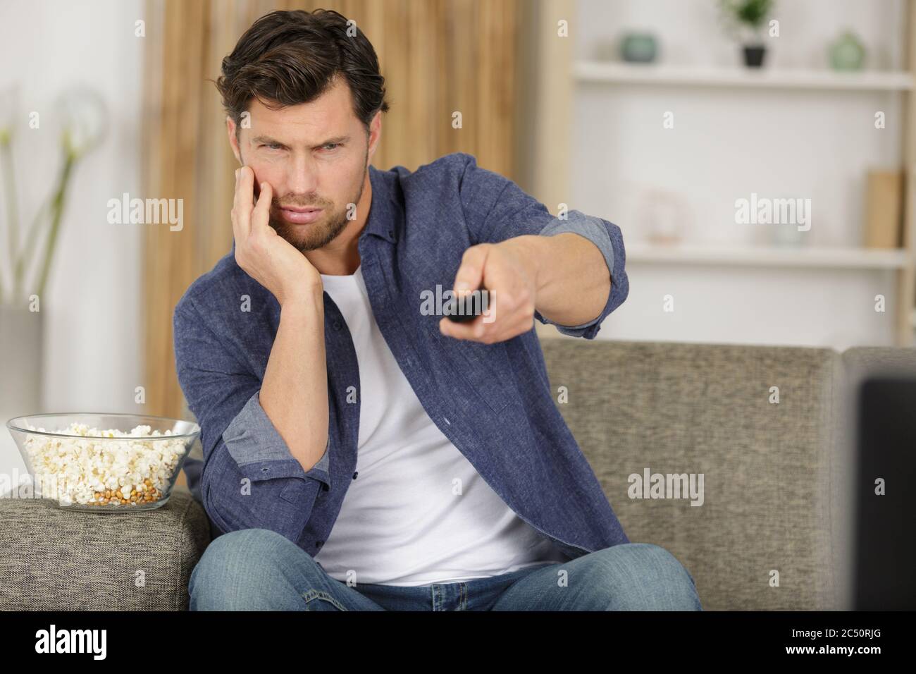 man with tv remote changing chanels Stock Photo - Alamy